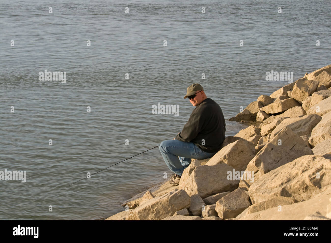 Man fishing in a reservoir off of a bank of rocks during the annual ...