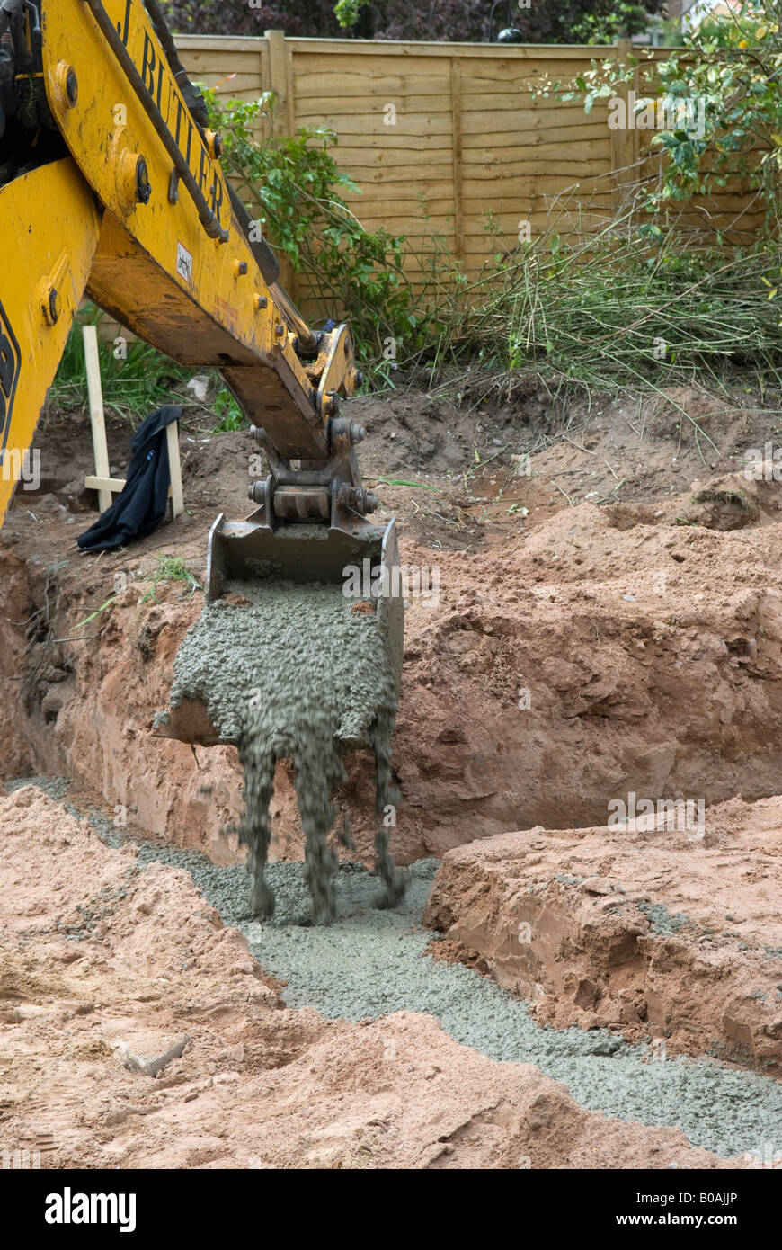 Digger moving concrete in a strip foundation Stock Photo - Alamy