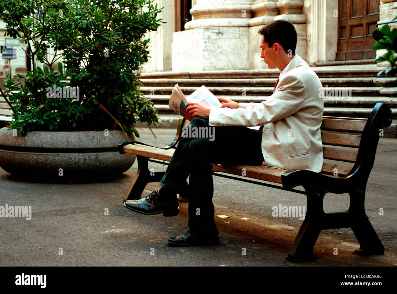 Man sitting on a bench, reading a newspaper, Rome, Italy Stock Photo ...