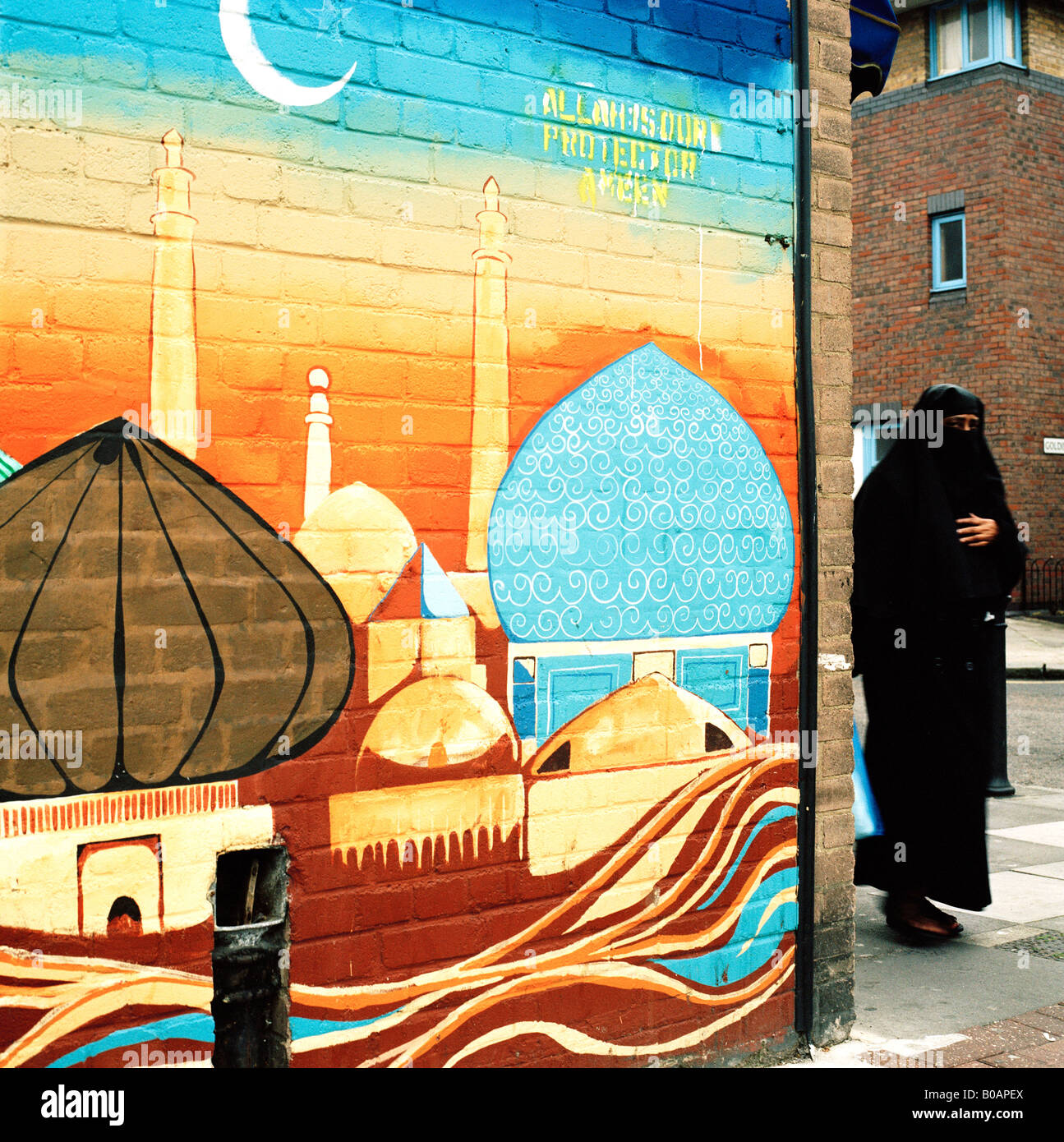 Muslim woman passing an Islamic mural in Whitechapel, East London Stock ...