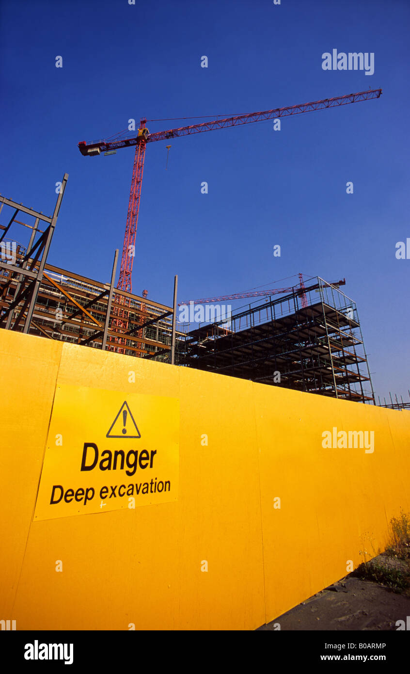 danger warning sign of deep construction by building site and crane ...