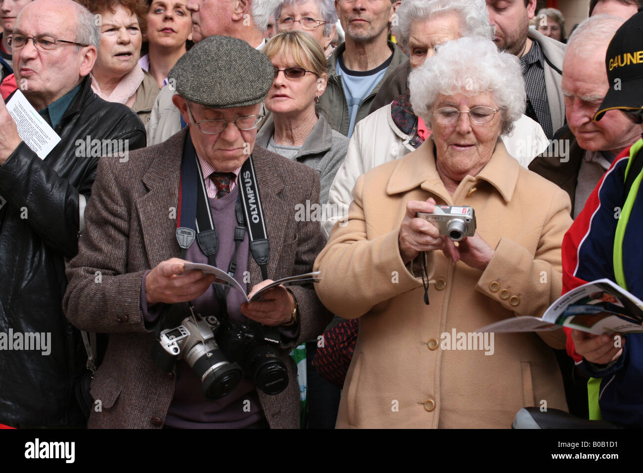 Elderly couple with their cameras taking photos in a crowd in the UK ...