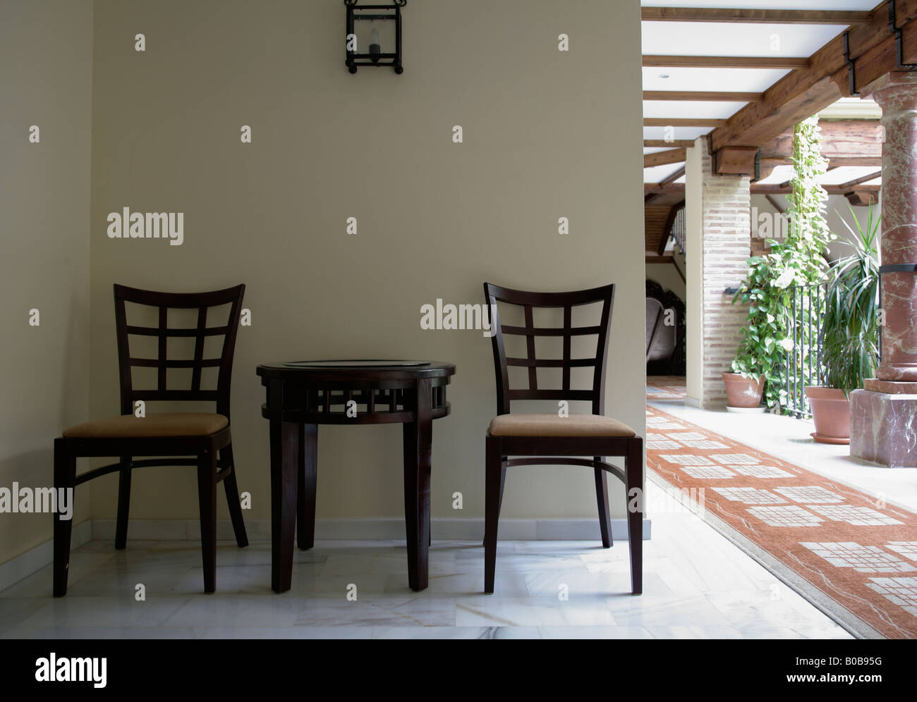 Corridor in building with two chairs, a table and plants Stock Photo ...