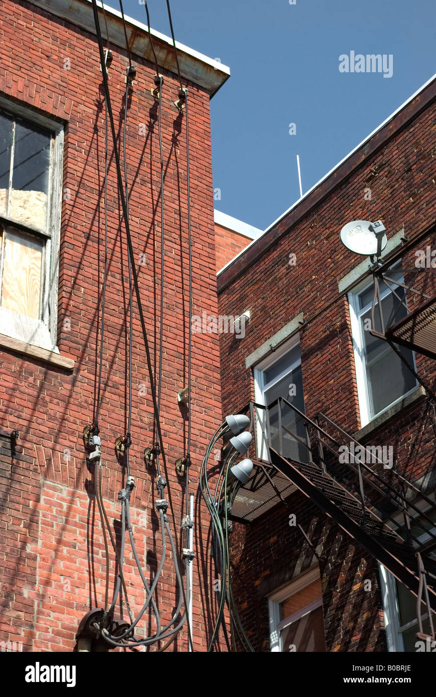 Cityscape shot of convergent brick buildings with wires, cables, fire ...