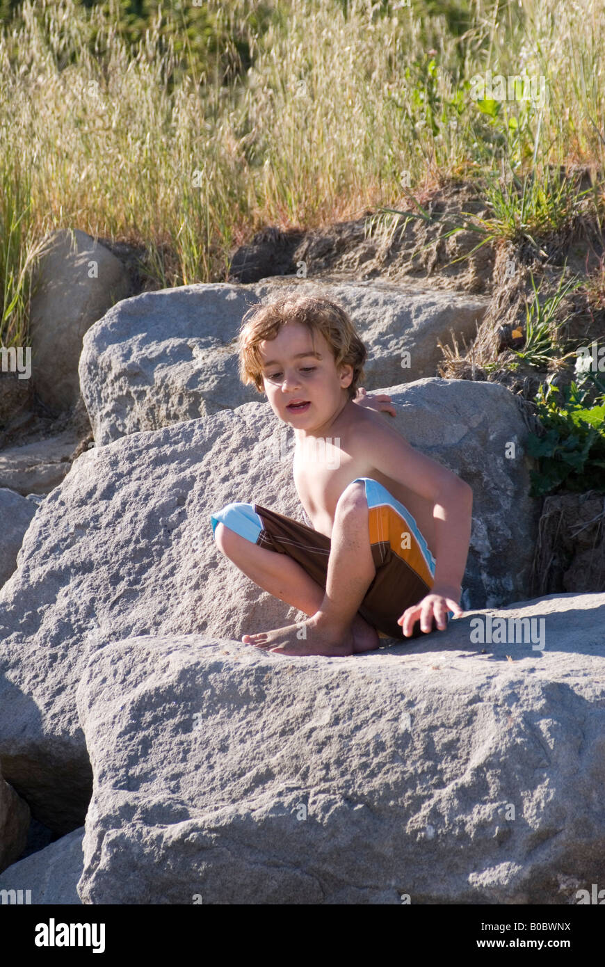 Boy in swimsuit plays on rocks Stock Photo - Alamy