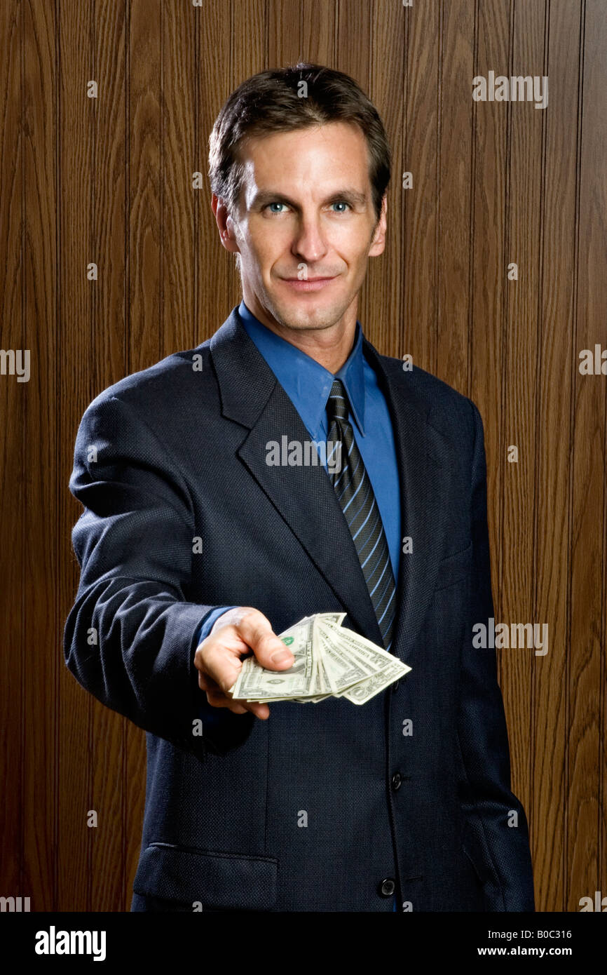 Businessman offering money smiling Stock Photo - Alamy