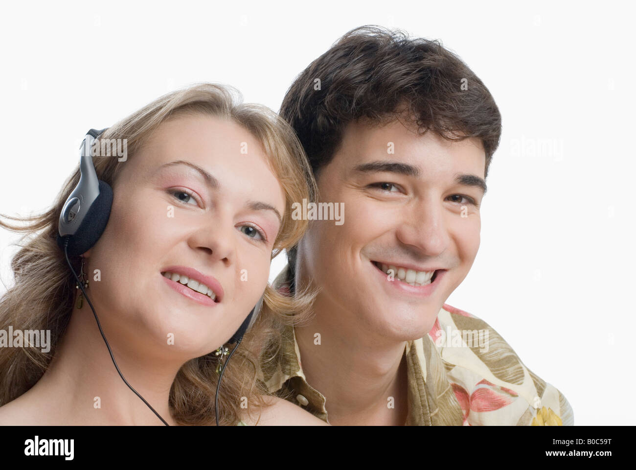 Portrait of a young woman listening to music with a young man beside ...