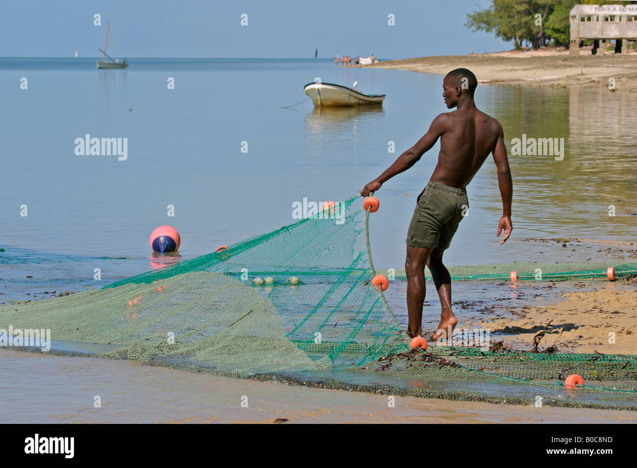 A mozambican fisherman pulling a fishing net from the water, Vilanculos ...