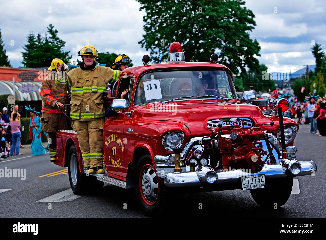 Image of a group of firefighters in uniform riding on the outside of an ...