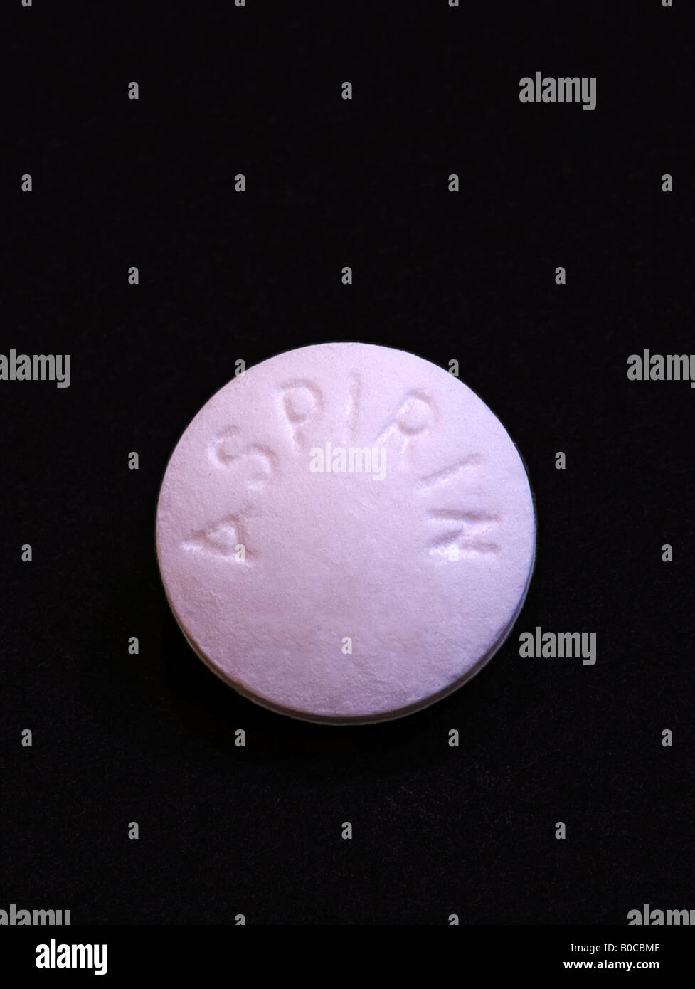 Image of a single asprin tablet laying face up on a black background ...