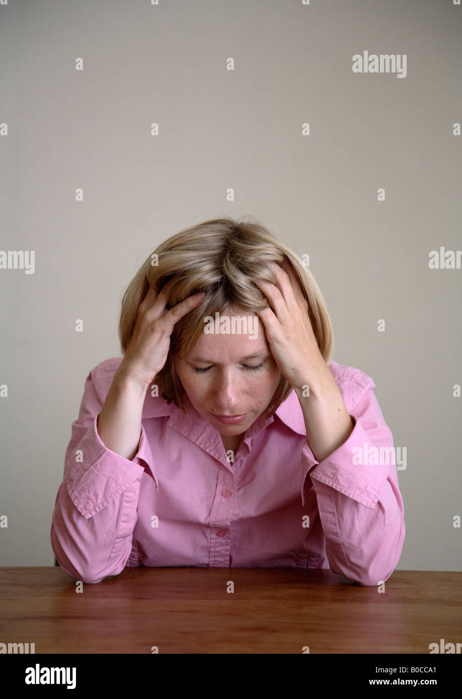 Tired woman sitting at a table Stock Photo - Alamy