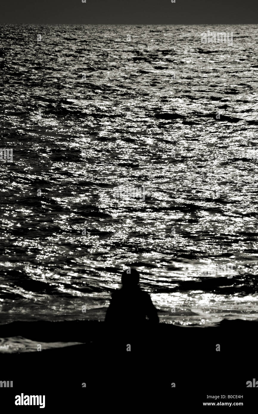 A figure gazing out to sea at night Stock Photo - Alamy
