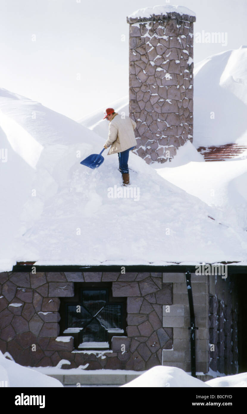 man clearing deep snow from house rooftop west yellowstone montana usa ...