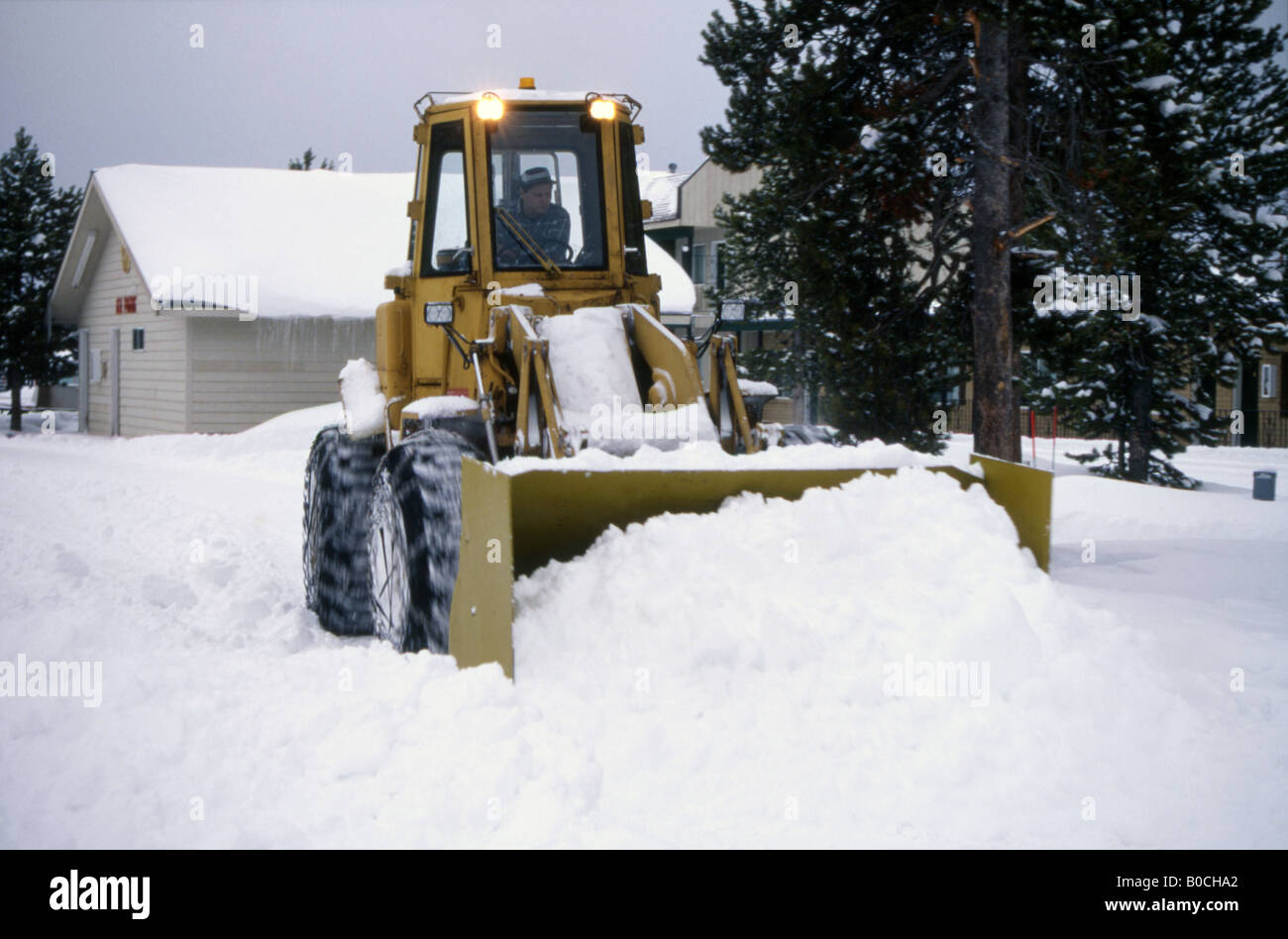 yellow industrial digger clearing deep snowdrifts from road in west ...
