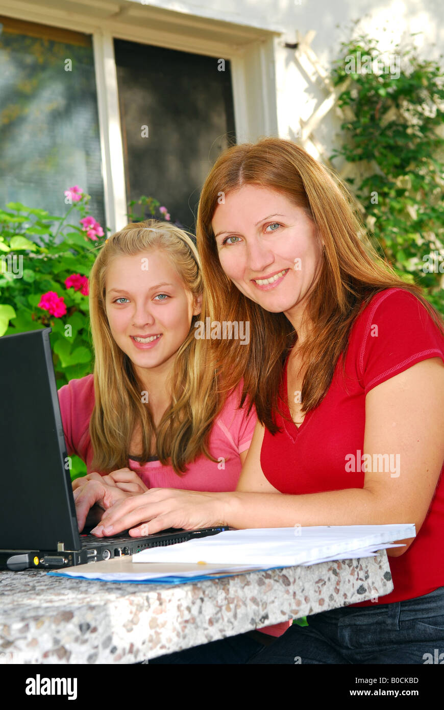 Mother and daughter working on computer at home in the backyard Stock ...