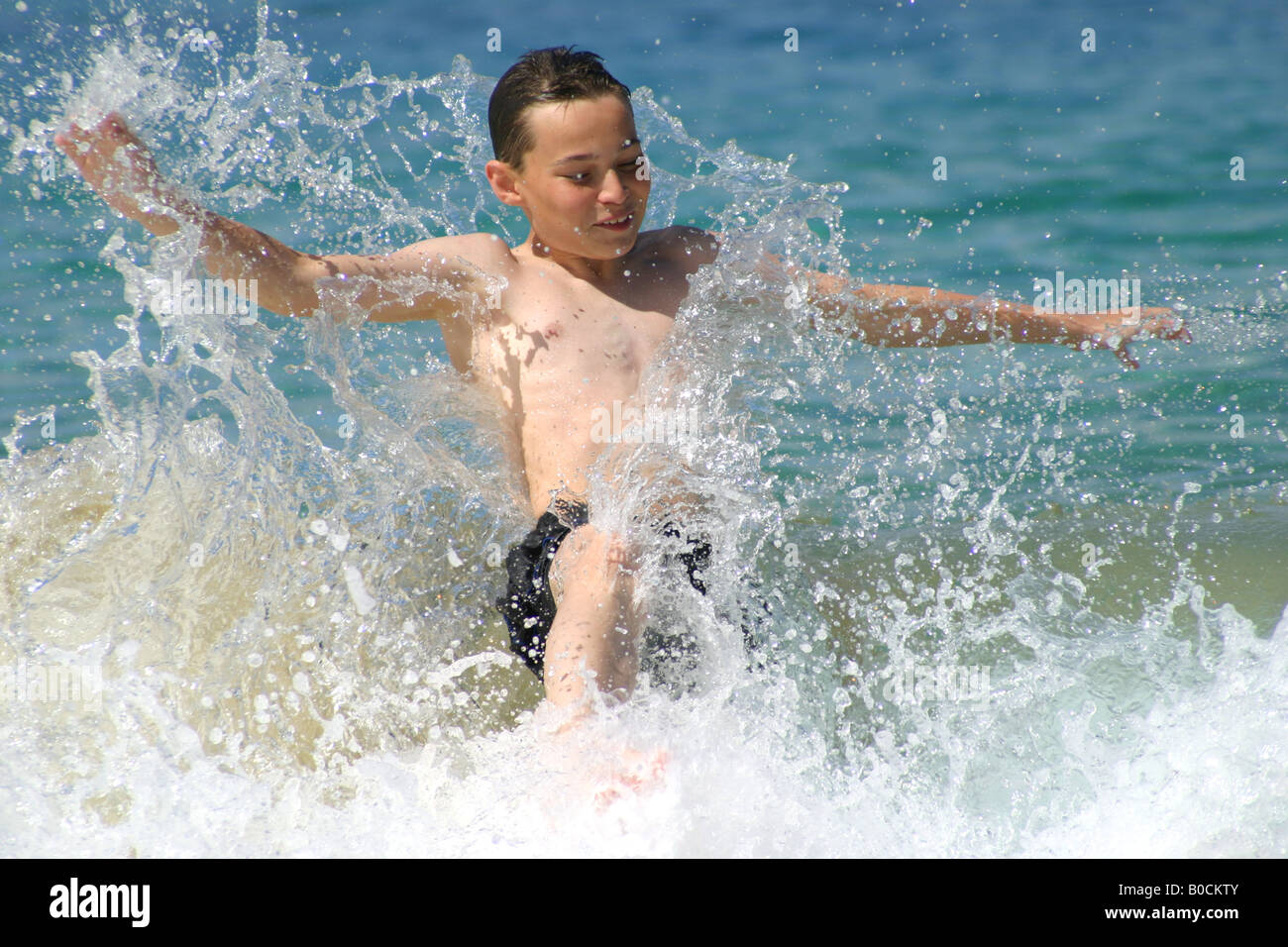 Young boy splashing in sea water Stock Photo - Alamy