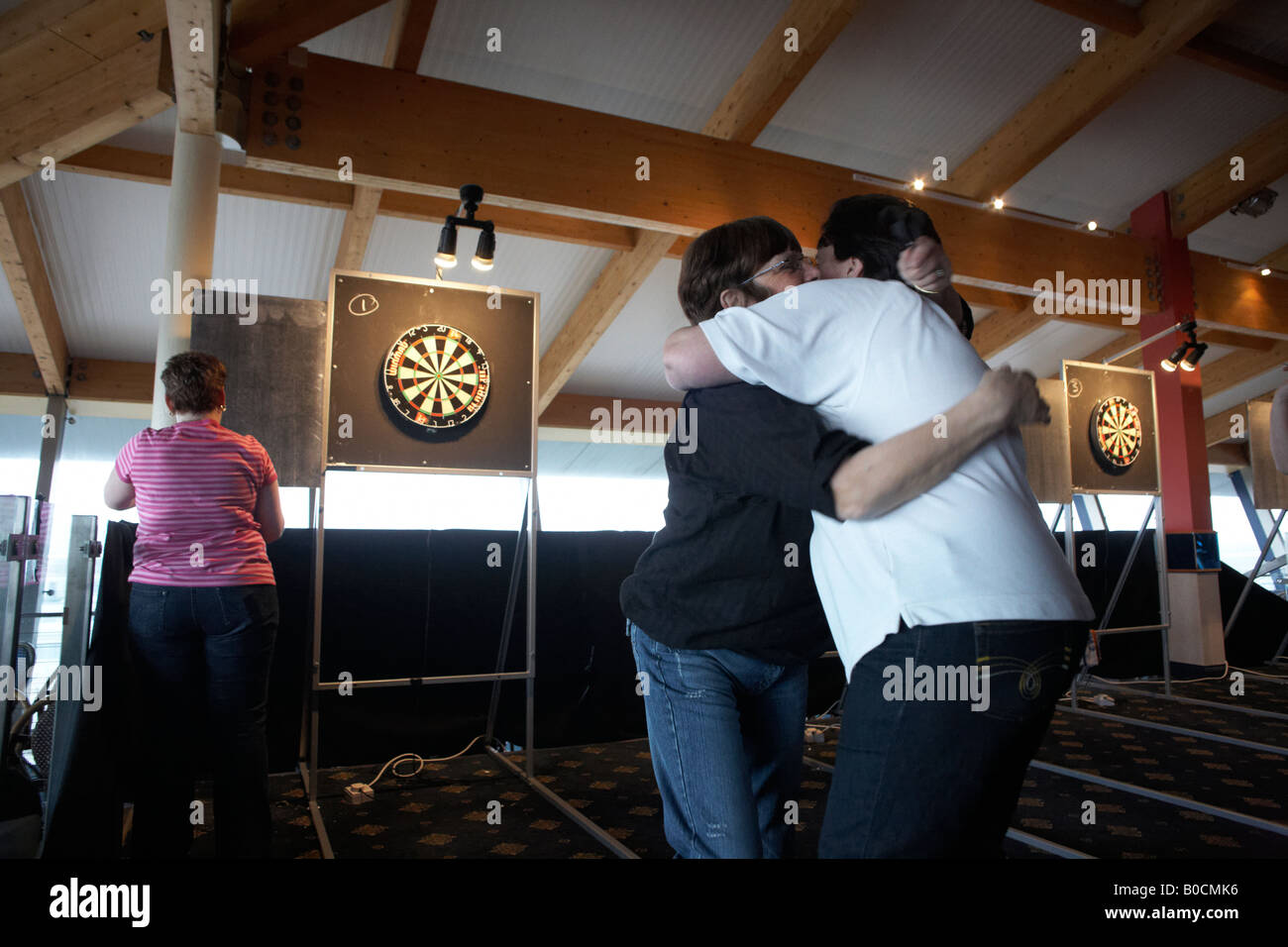 Winner and loser darts players hug affectionately after a preliminary ...
