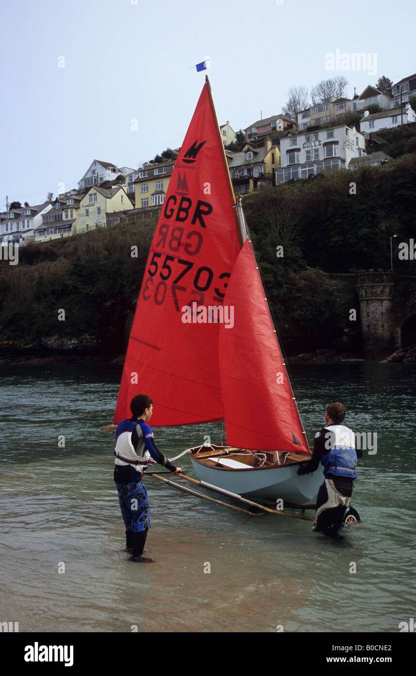 Two Youths Launching Sailling Dinghy In Looe Cornwall Stock Photo - Alamy