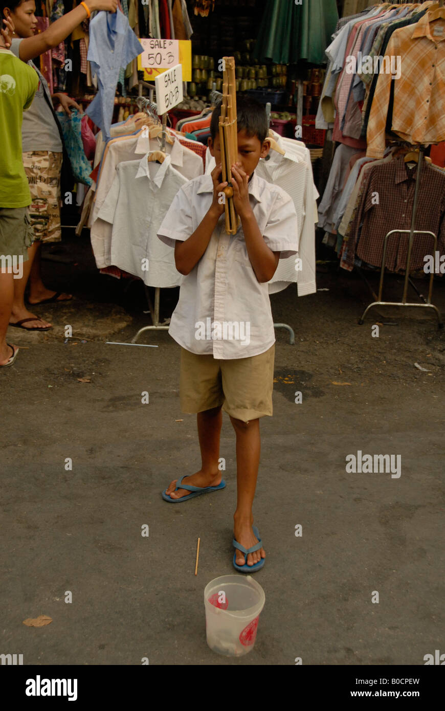 little school boy is blowing traditional mouth organ to get donation ...