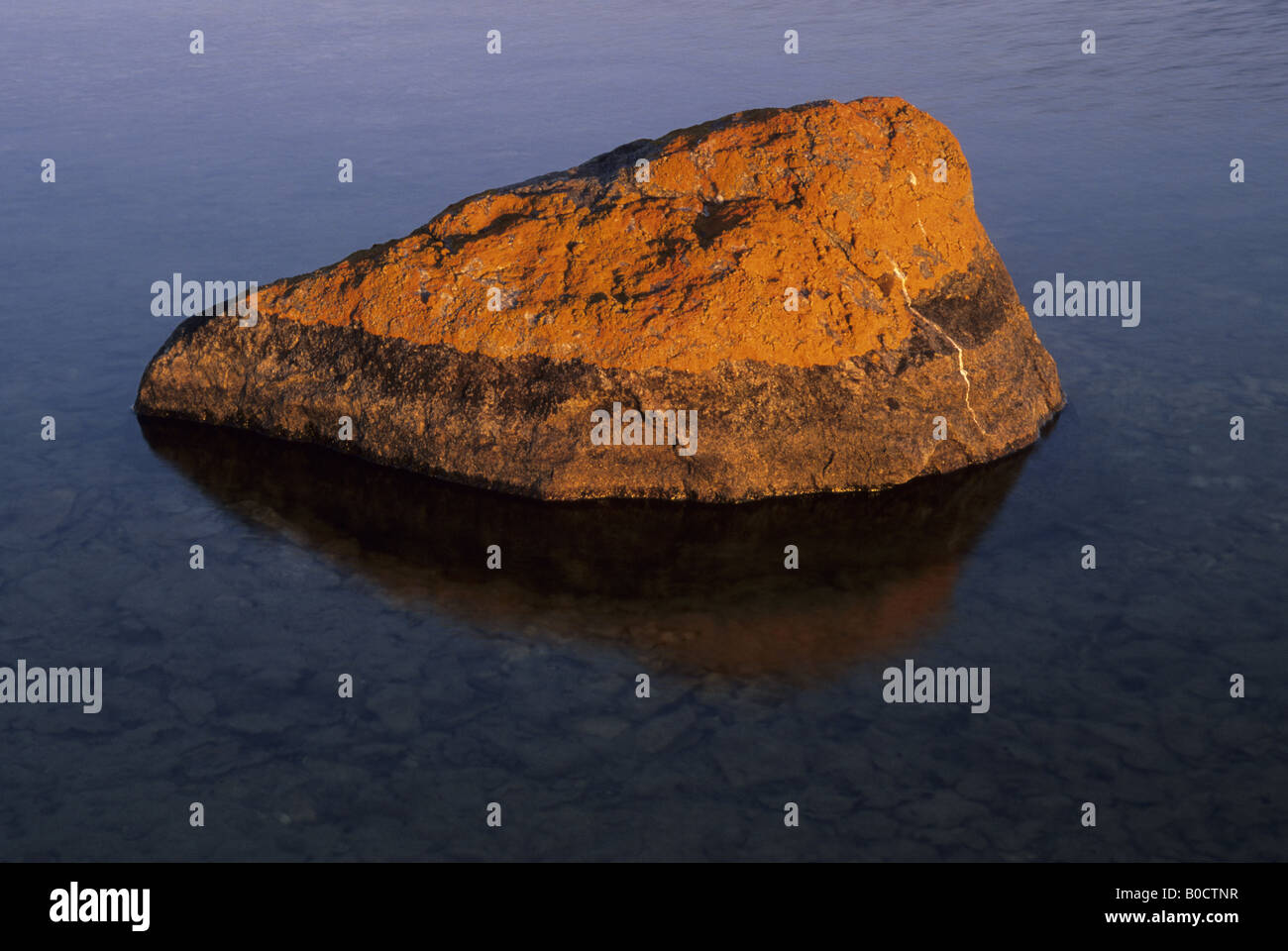 A large boulder and its reflection in water Stock Photo - Alamy