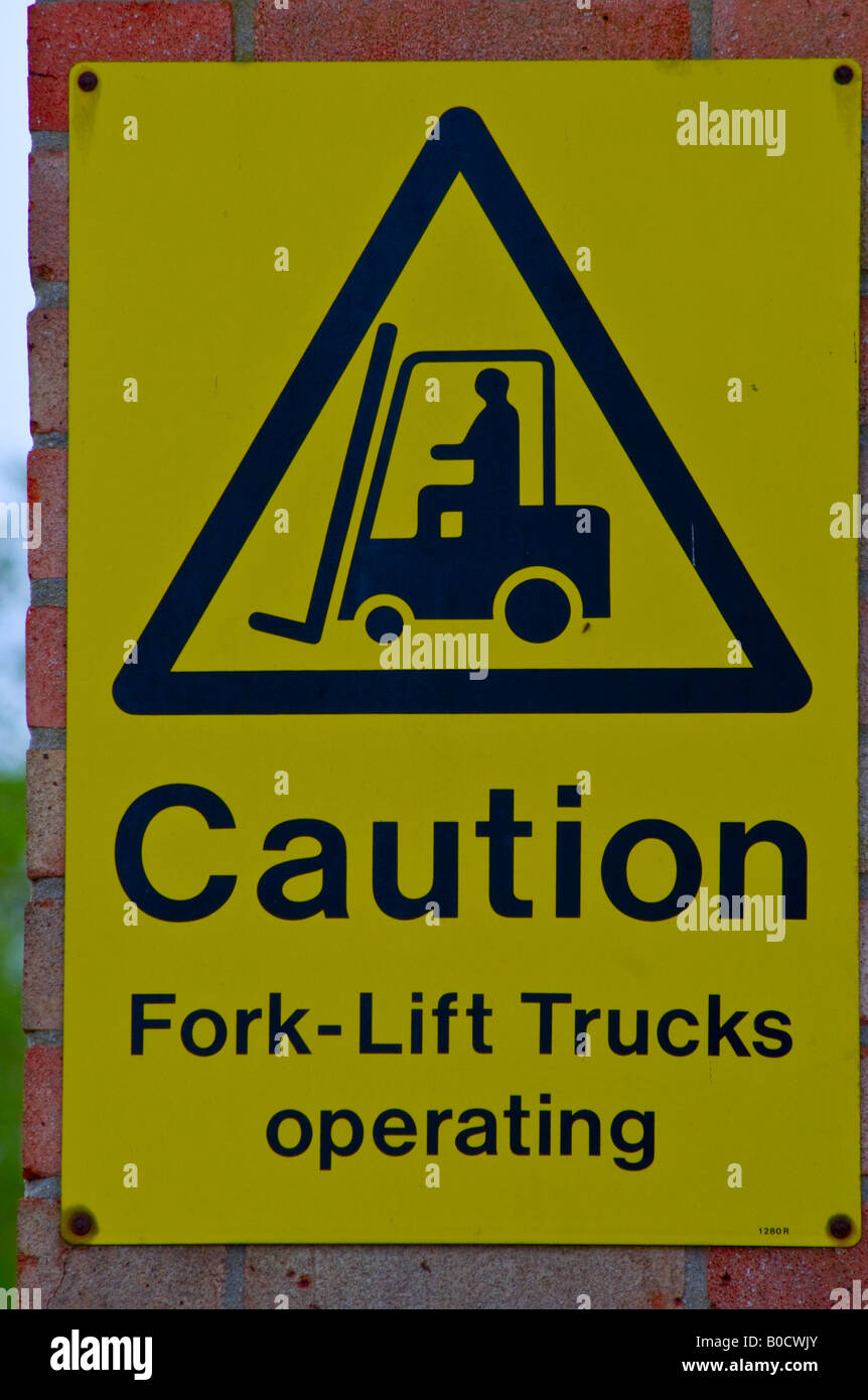 Yellow Caution fork lift trucks operating sign, portrait photograph ...