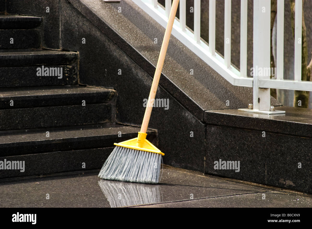 Broom leaning against a metal reailing Stock Photo - Alamy