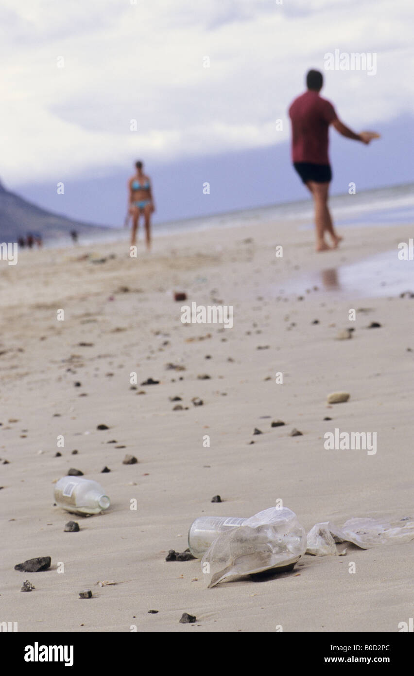 Adult couple playing beach tennis near bottles washed out of sea ...