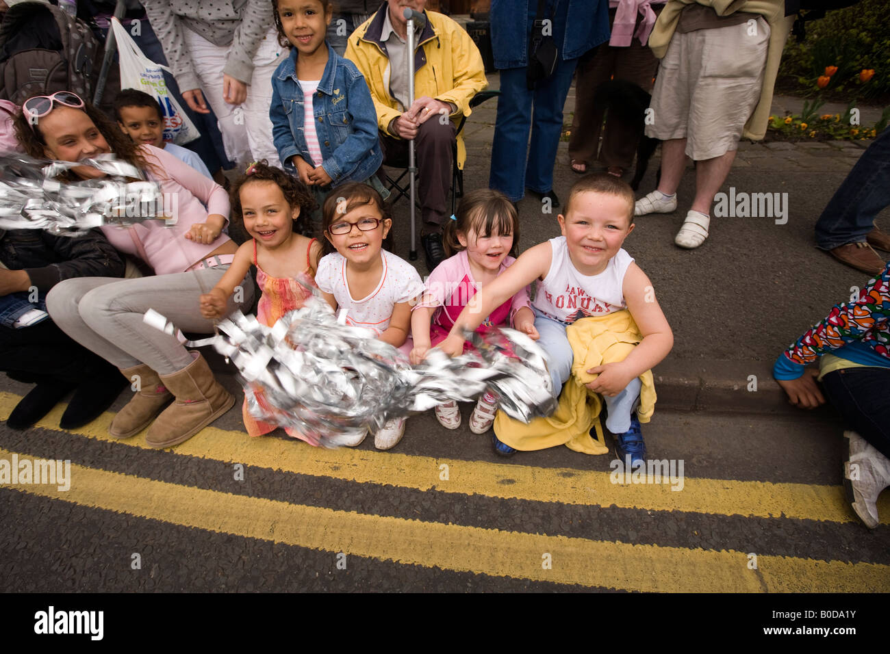 UK Cheshire Knutsford Royal May Day Procession children sat on pavement ...