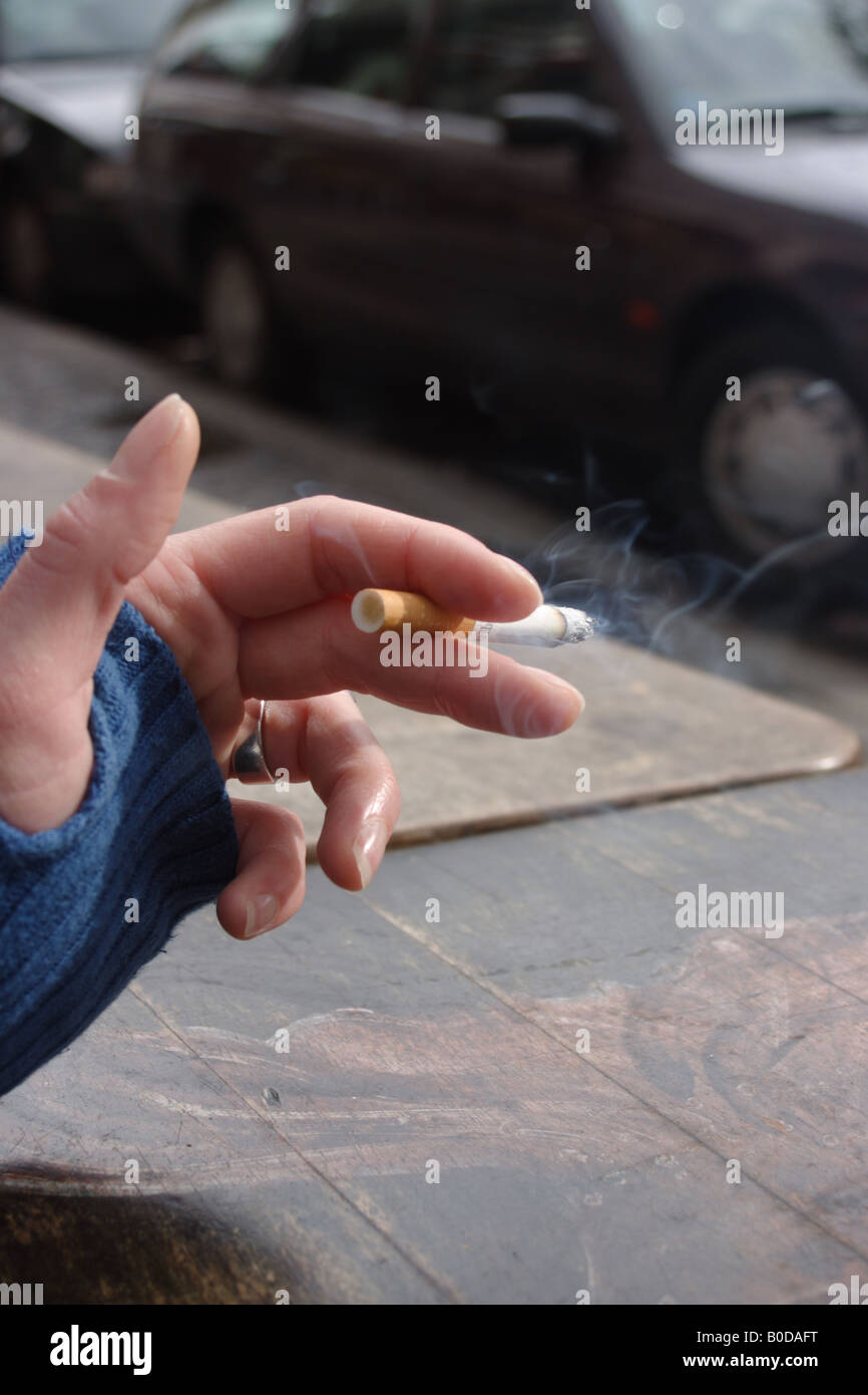 lit cigarette in hand on a city street Stock Photo - Alamy