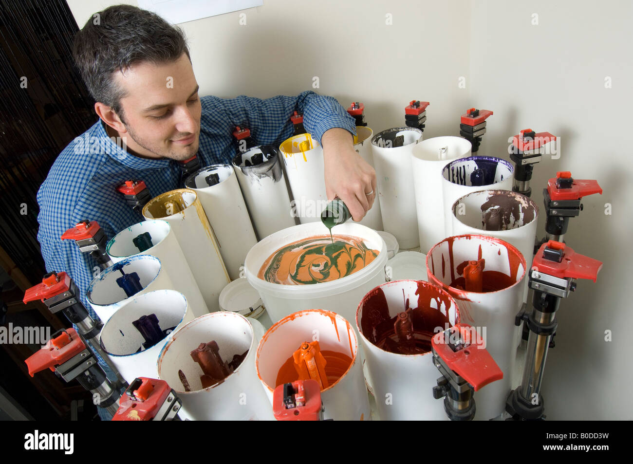 A man mixing paints and blending colours in a workshop making bespoke ...