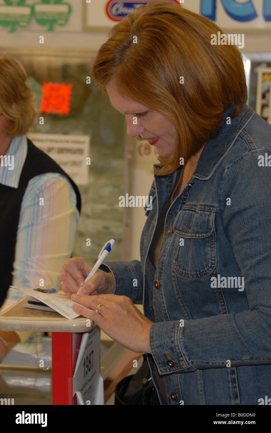 A woman pays for her groceries by writing a check Stock Photo - Alamy