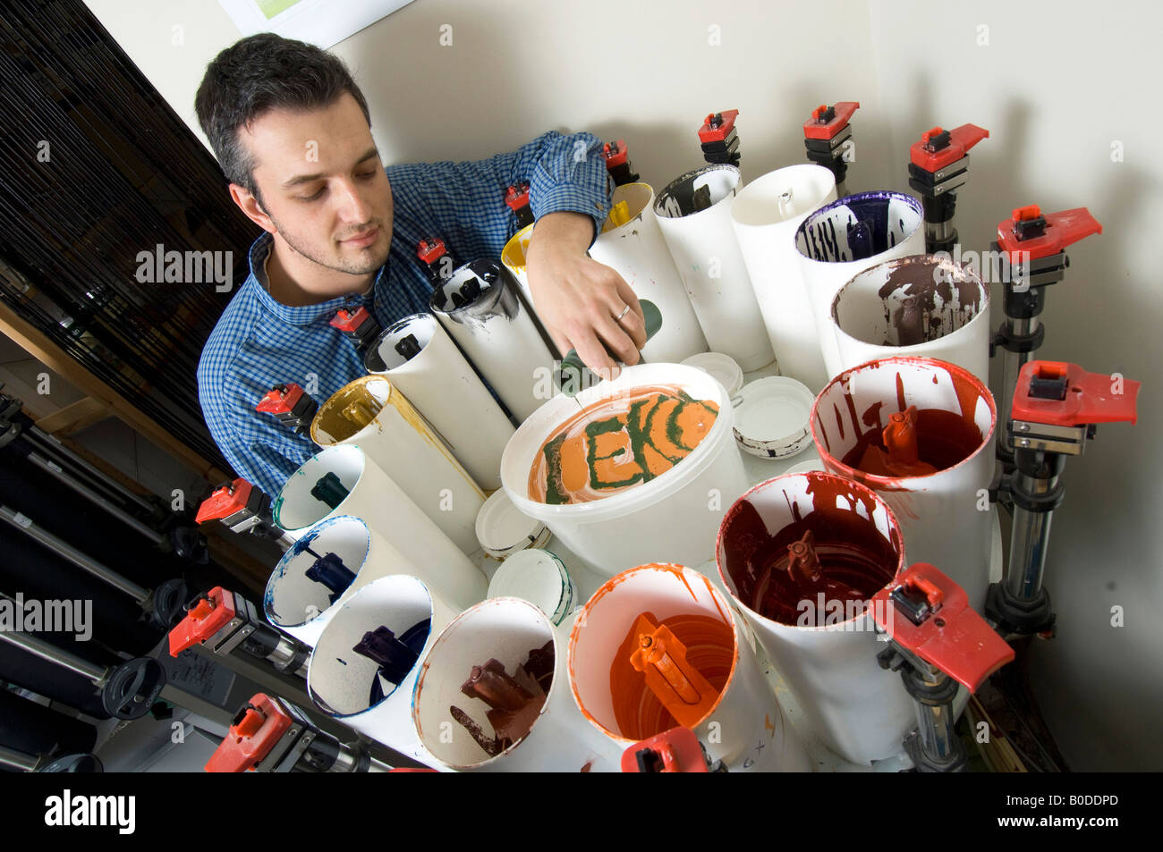 A man mixing paints and blending colours in a workshop making bespoke ...