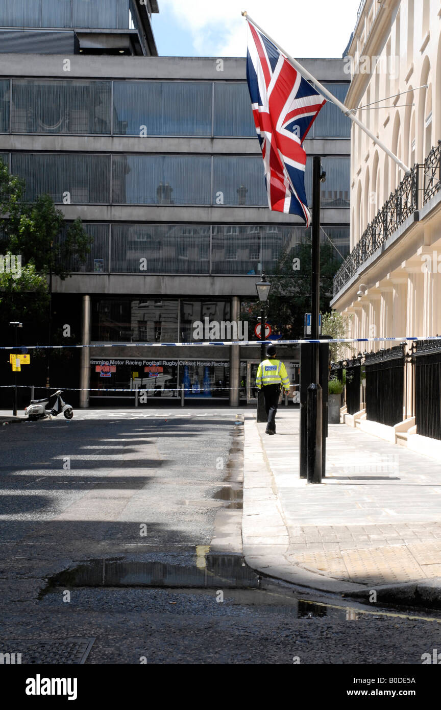 Metropolitan police officer walks under a large union jack on patrol ...