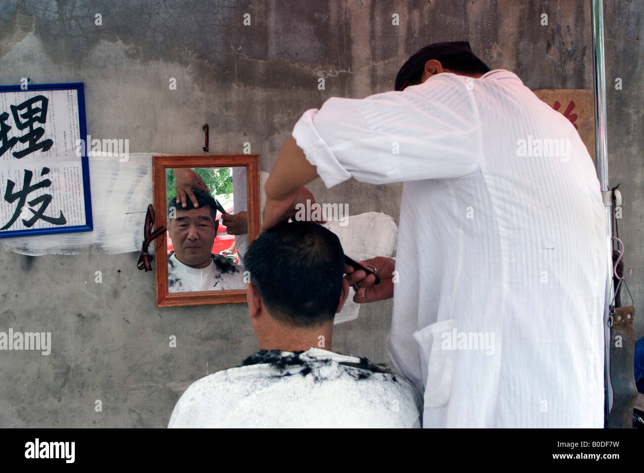 A man gets a haircut from a street barber Beijing China Stock Photo - Alamy