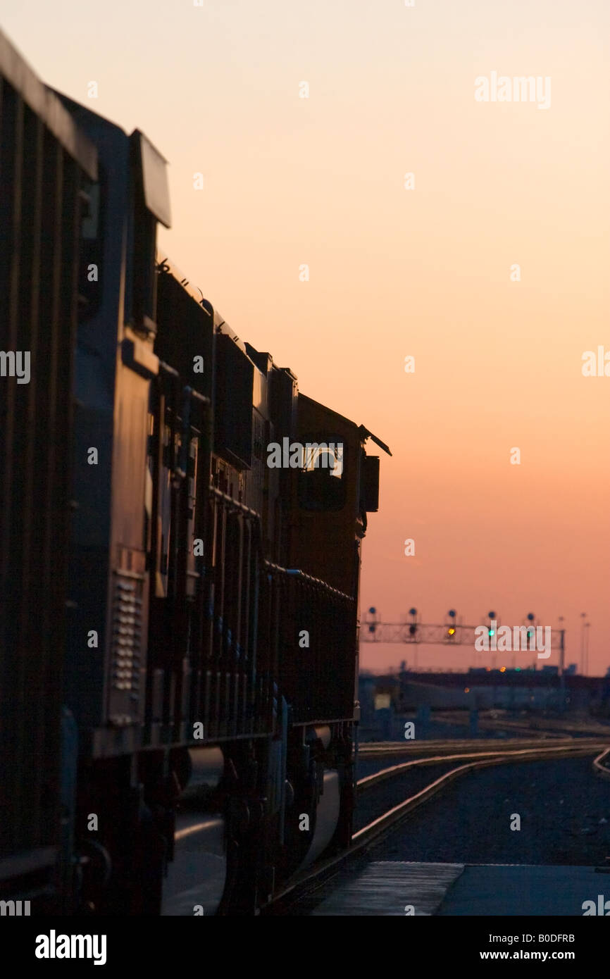 A locomotive engineer is silhouetted in the cab window of his ...
