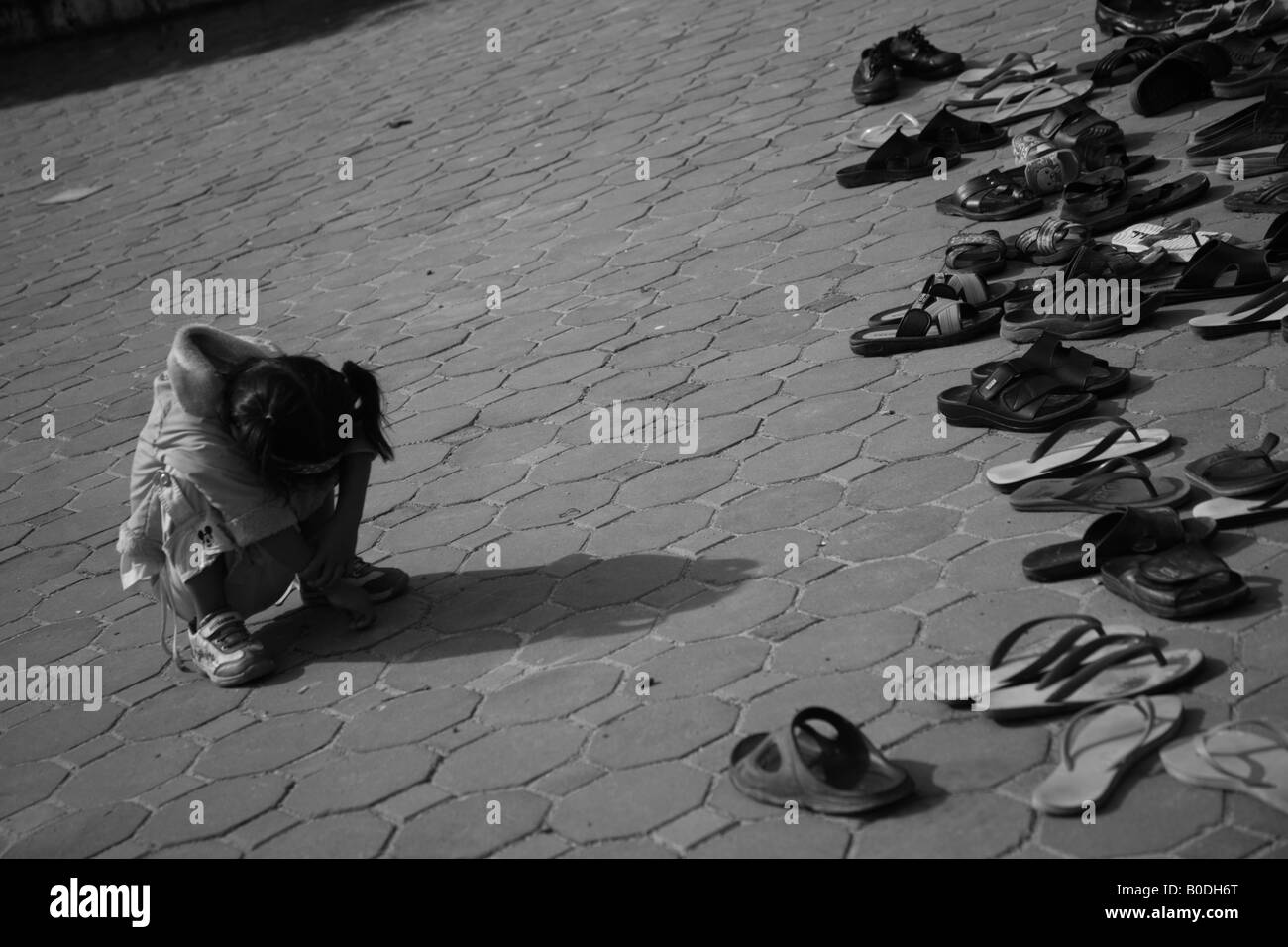 lonesome child praying outside mosgue amongst a thousand shoes , koh ...