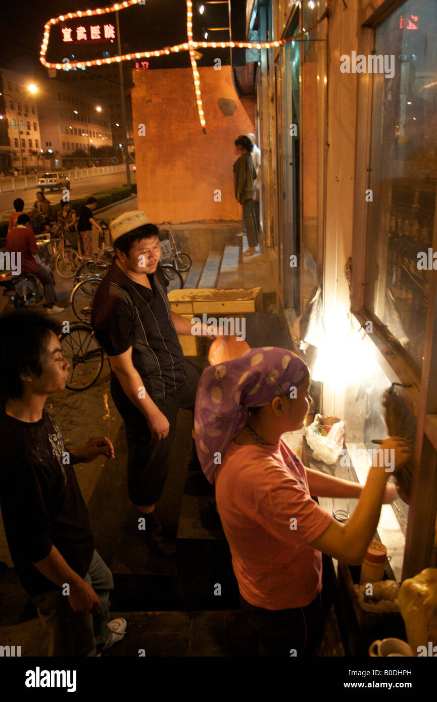A muslim couple from western China prepare barbecued meat skewers for a ...