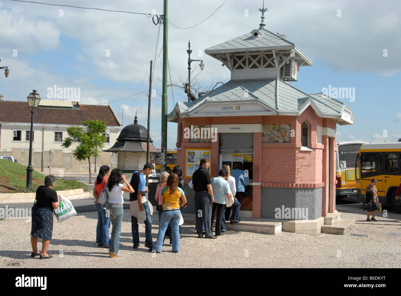 Bus passengers form a queue at a bus kiosk to purchase their tickets at ...