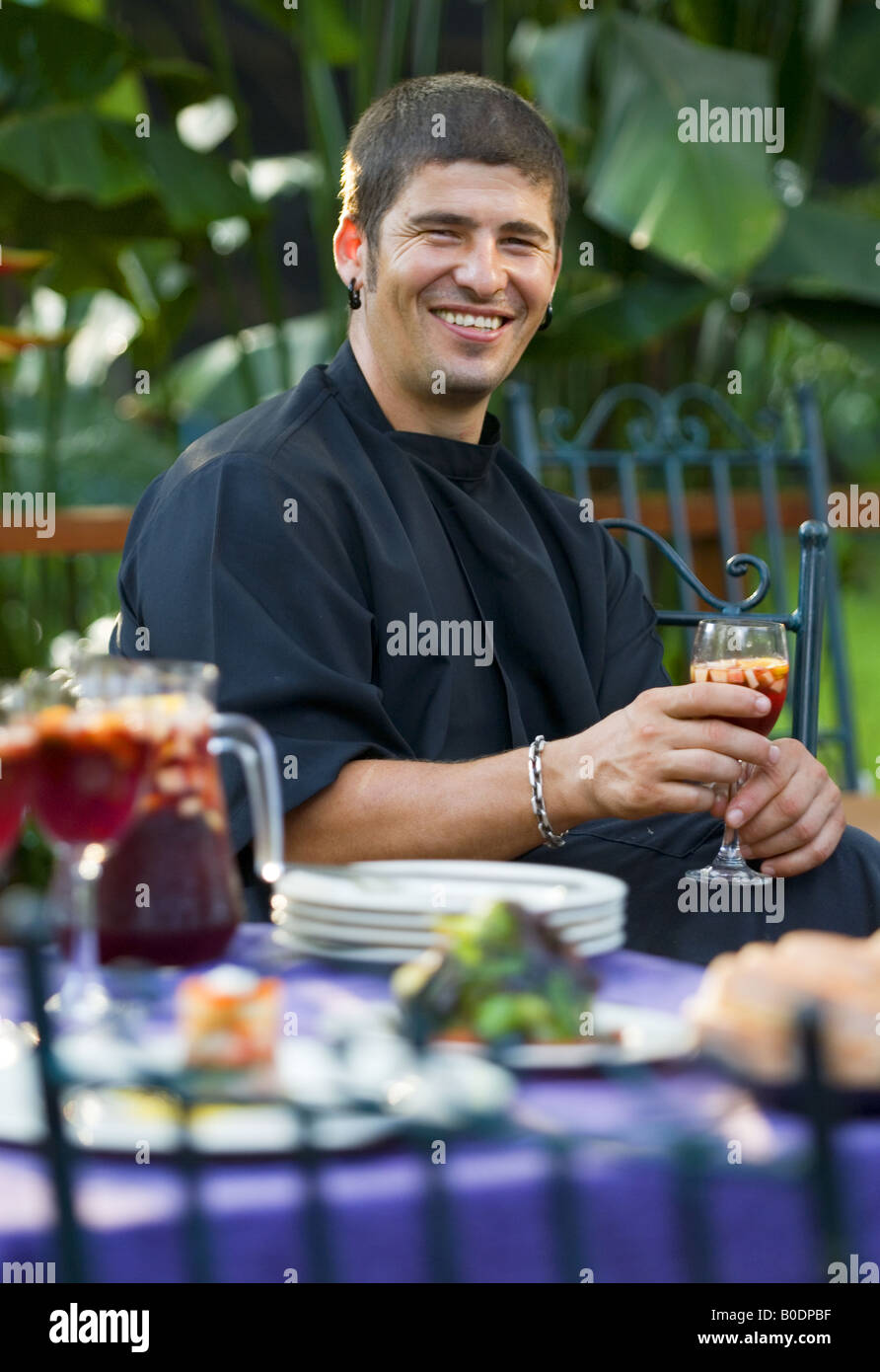 A smiling Spanish chef sits at a colorful table of Mediterranean food ...