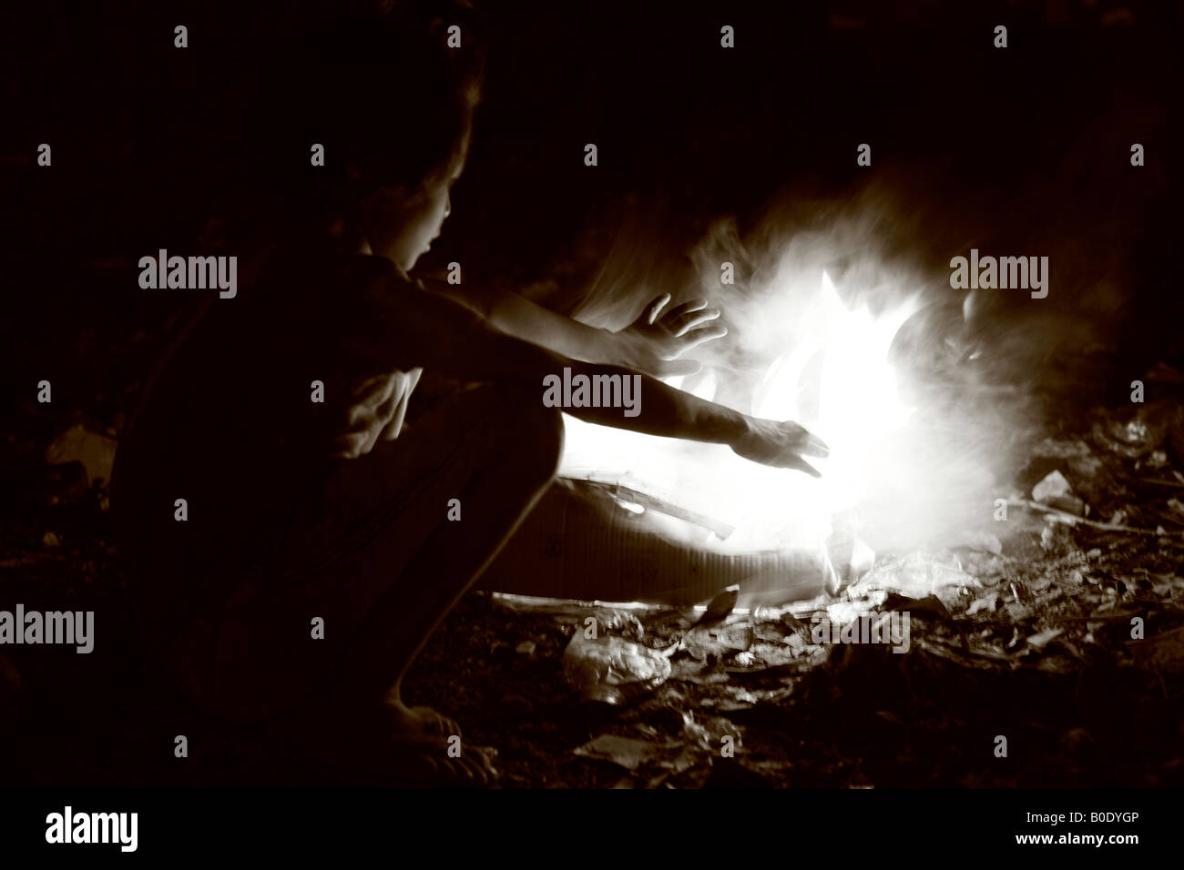 poor street kid heating herself with fire nepal Stock Photo - Alamy