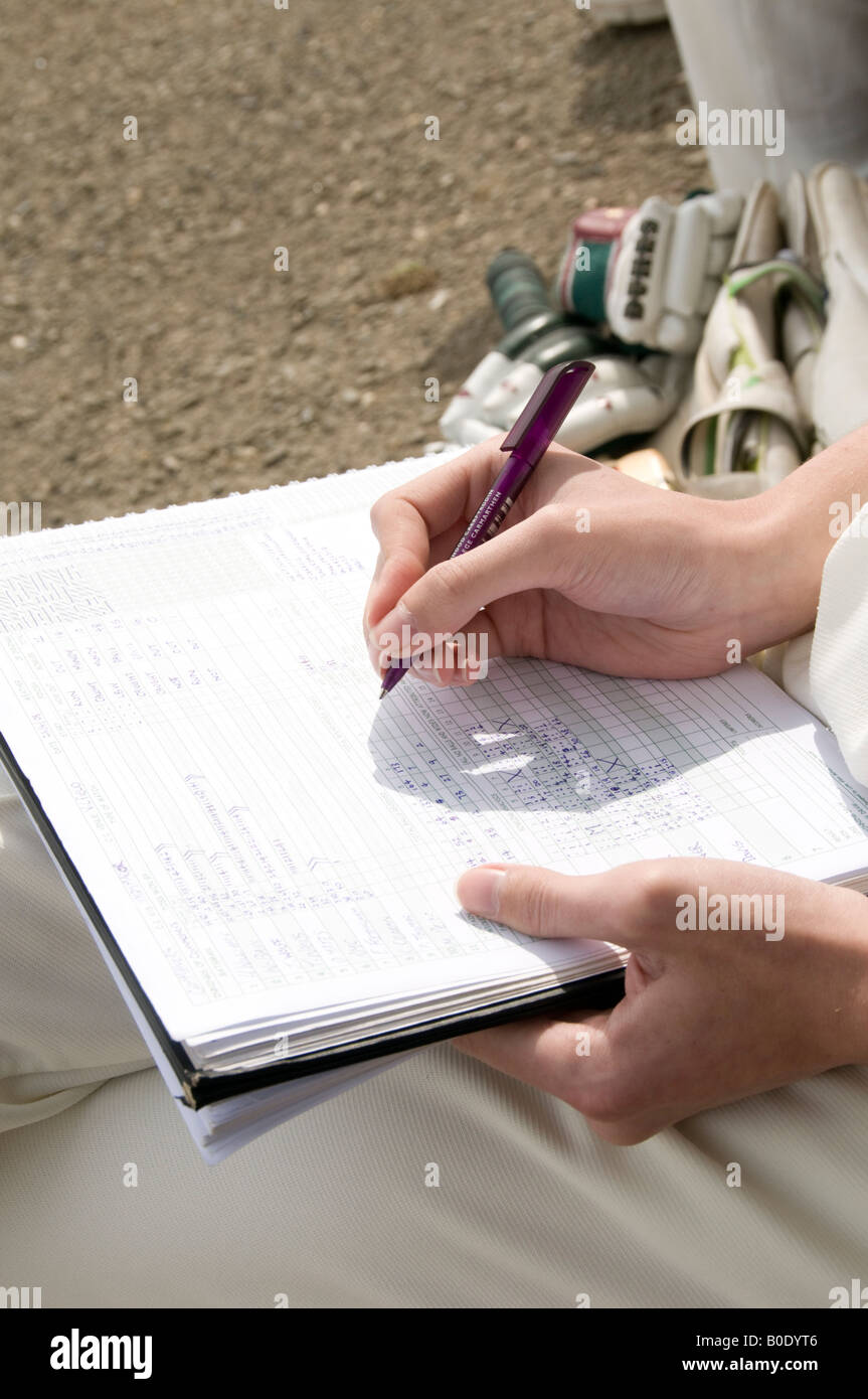 Scorer recording runs and overs and marking the score card at a cricket ...