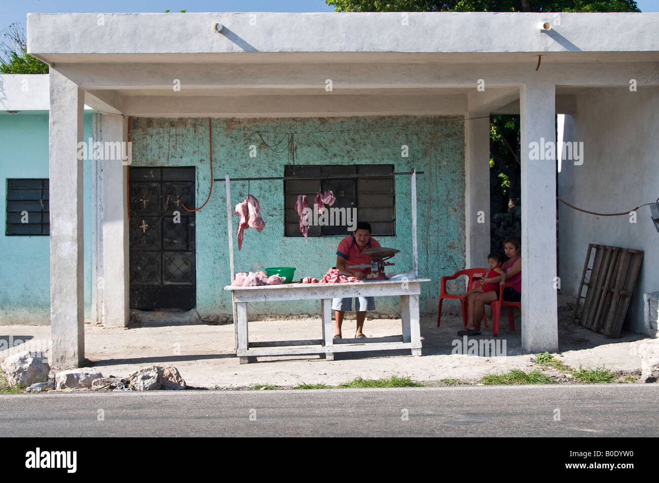 Road-side butcher's shop near Merida, Mexico. The wife and child watch ...