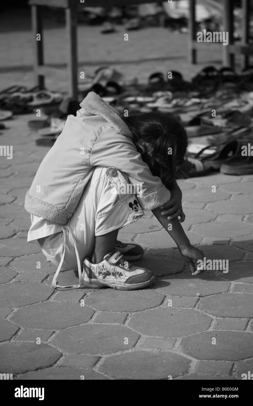 lonesome child praying outside mosgue amongst a thousand shoes , koh ...