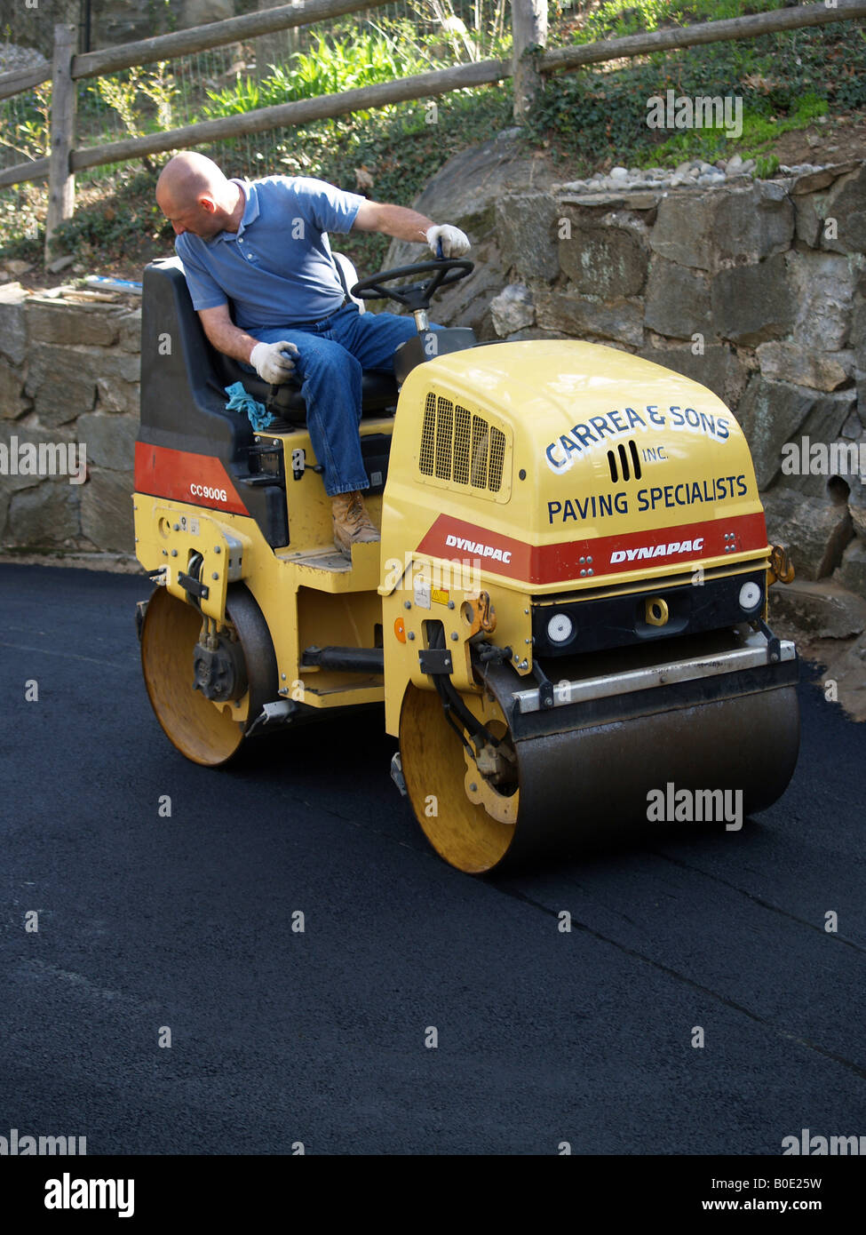 Workman rolling fresh asphalt on newly constructed driveway Stock Photo ...