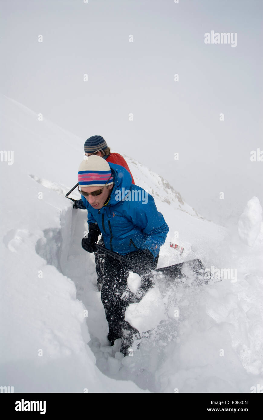 Two skiers digging an avalanche pit in the snow- testing the snowpack ...
