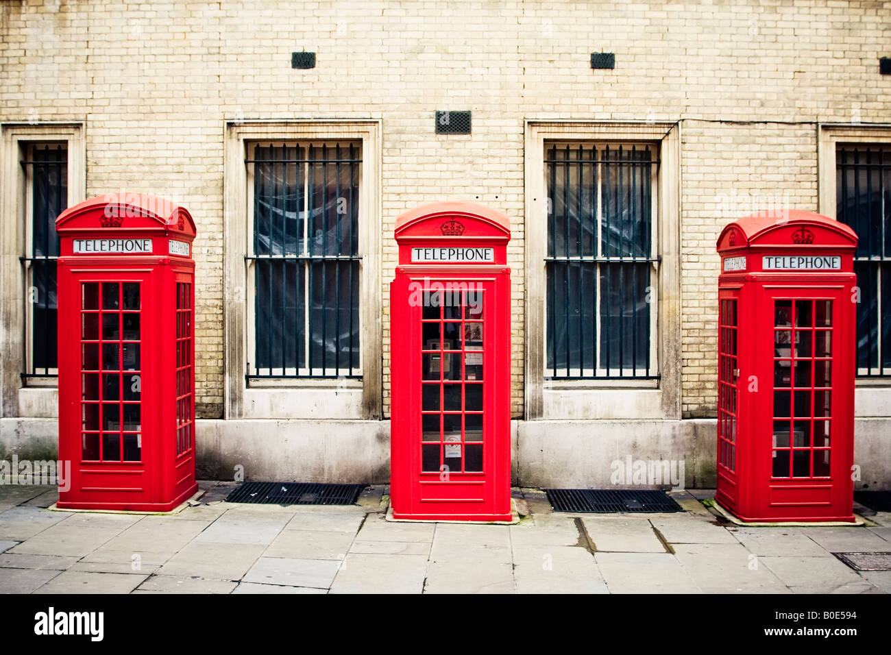 Three red phone boxes over grunge wall background Stock Photo - Alamy