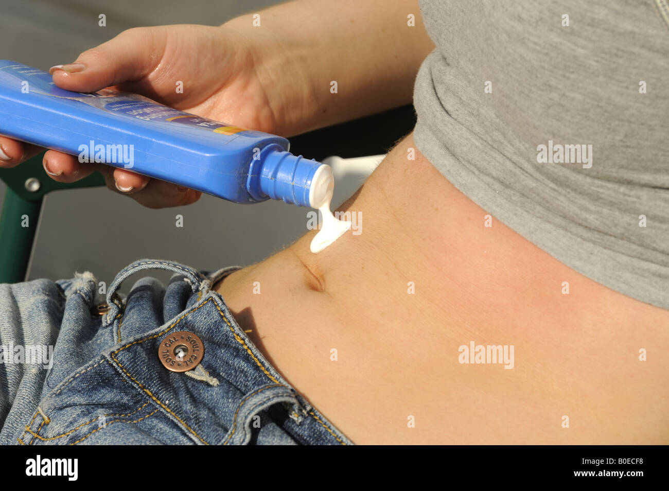 Nivea protective suncream being applied to bare skin on female stomach ...