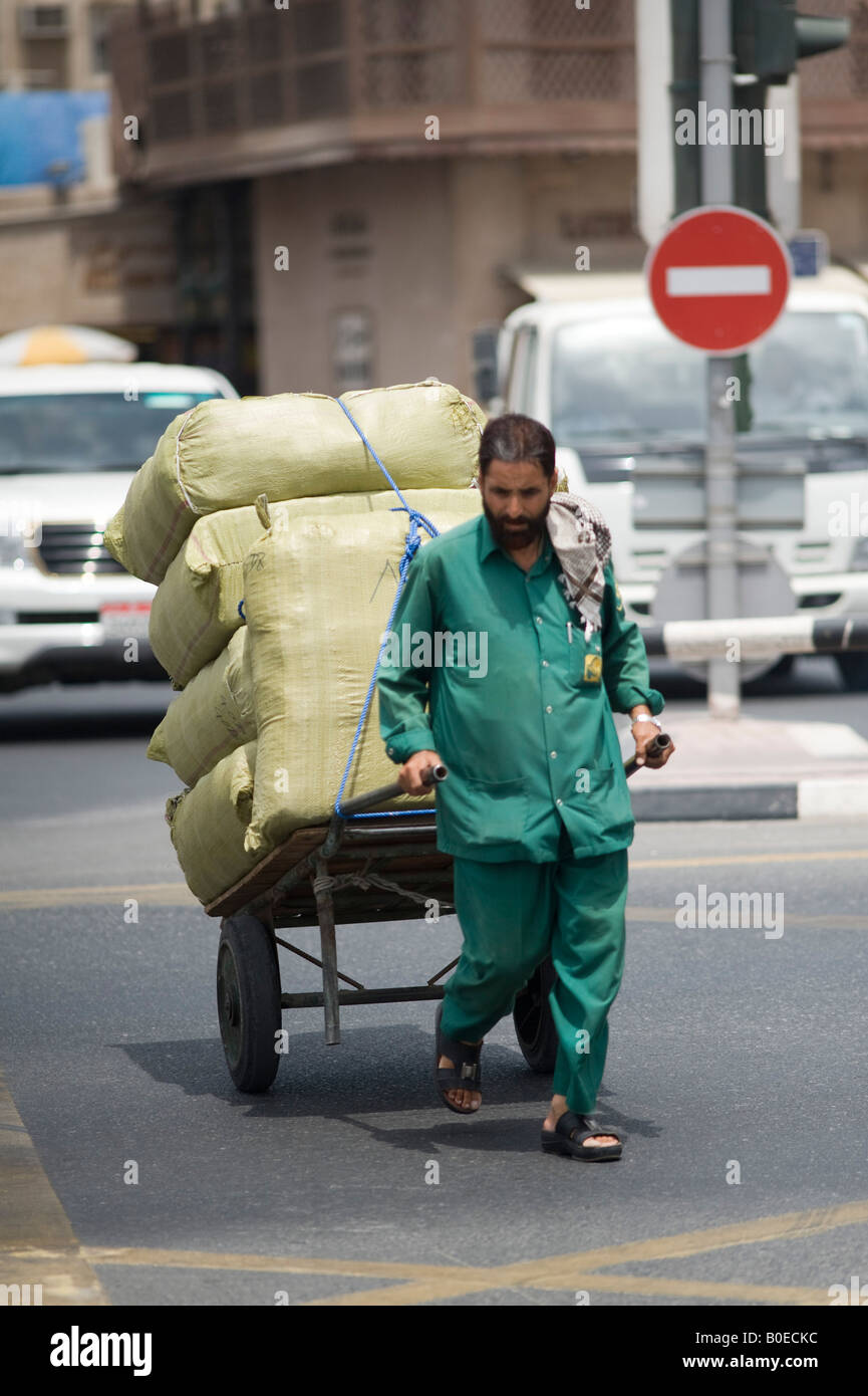 Dubai, United Arab Emirates (UAE). A porter pulling a heavily laden ...