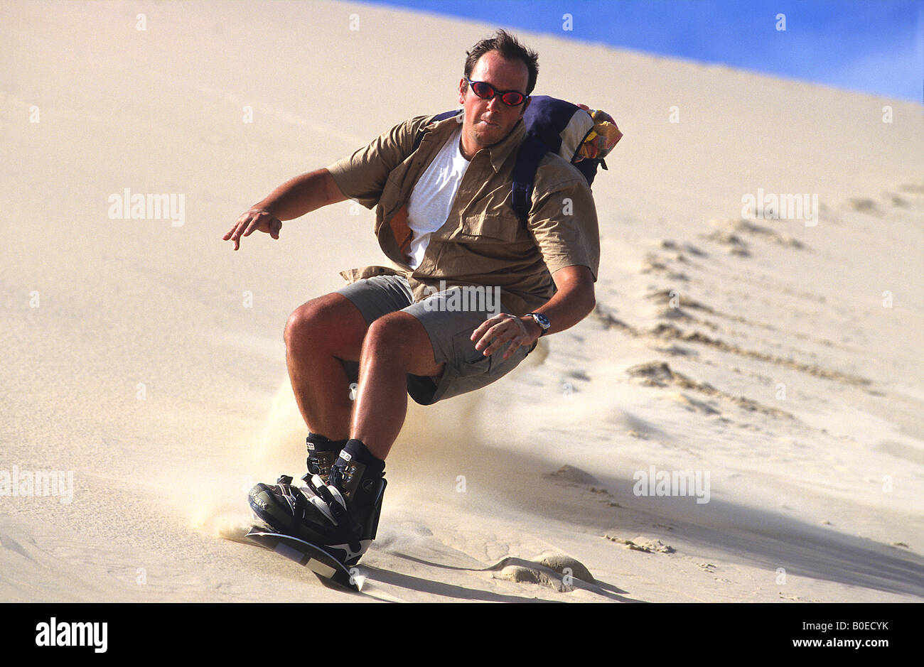 Man riding sandboarding down sand dune at high speed Stock Photo - Alamy