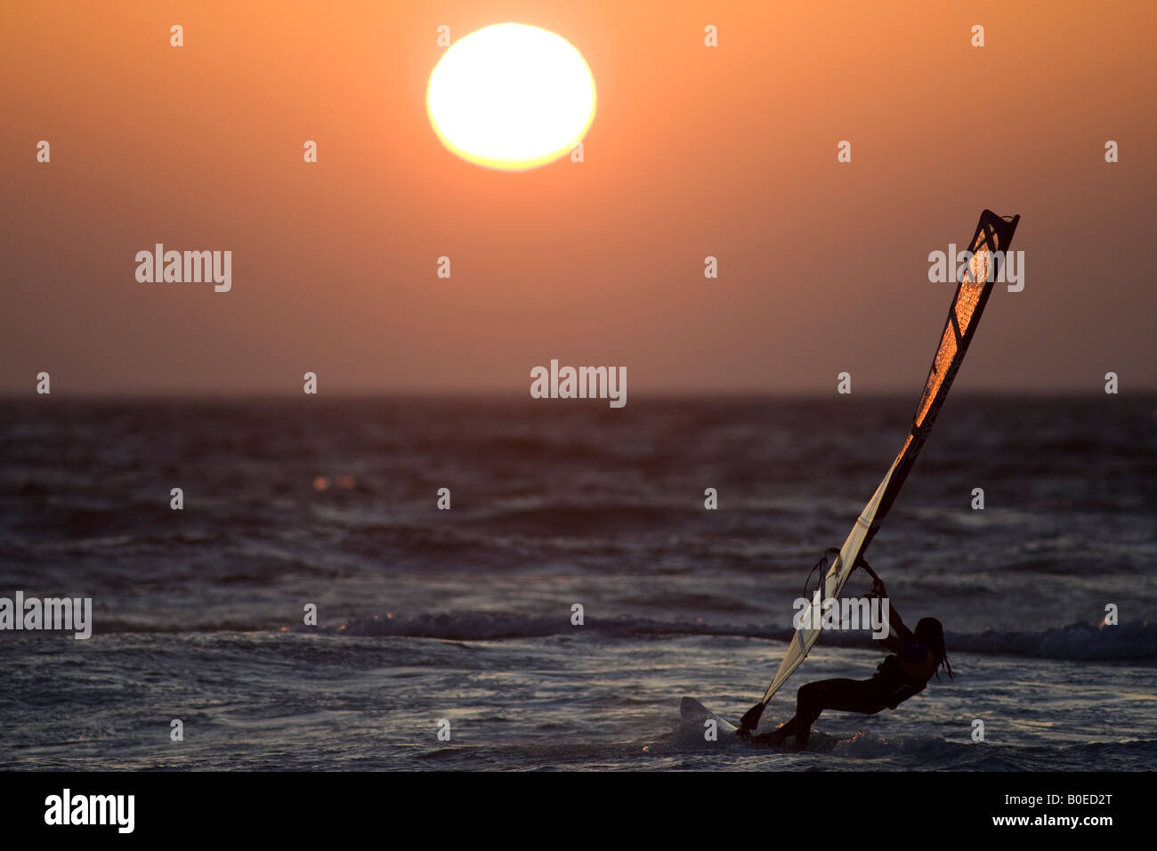 A female windsurfer sails into the sunset Stock Photo - Alamy